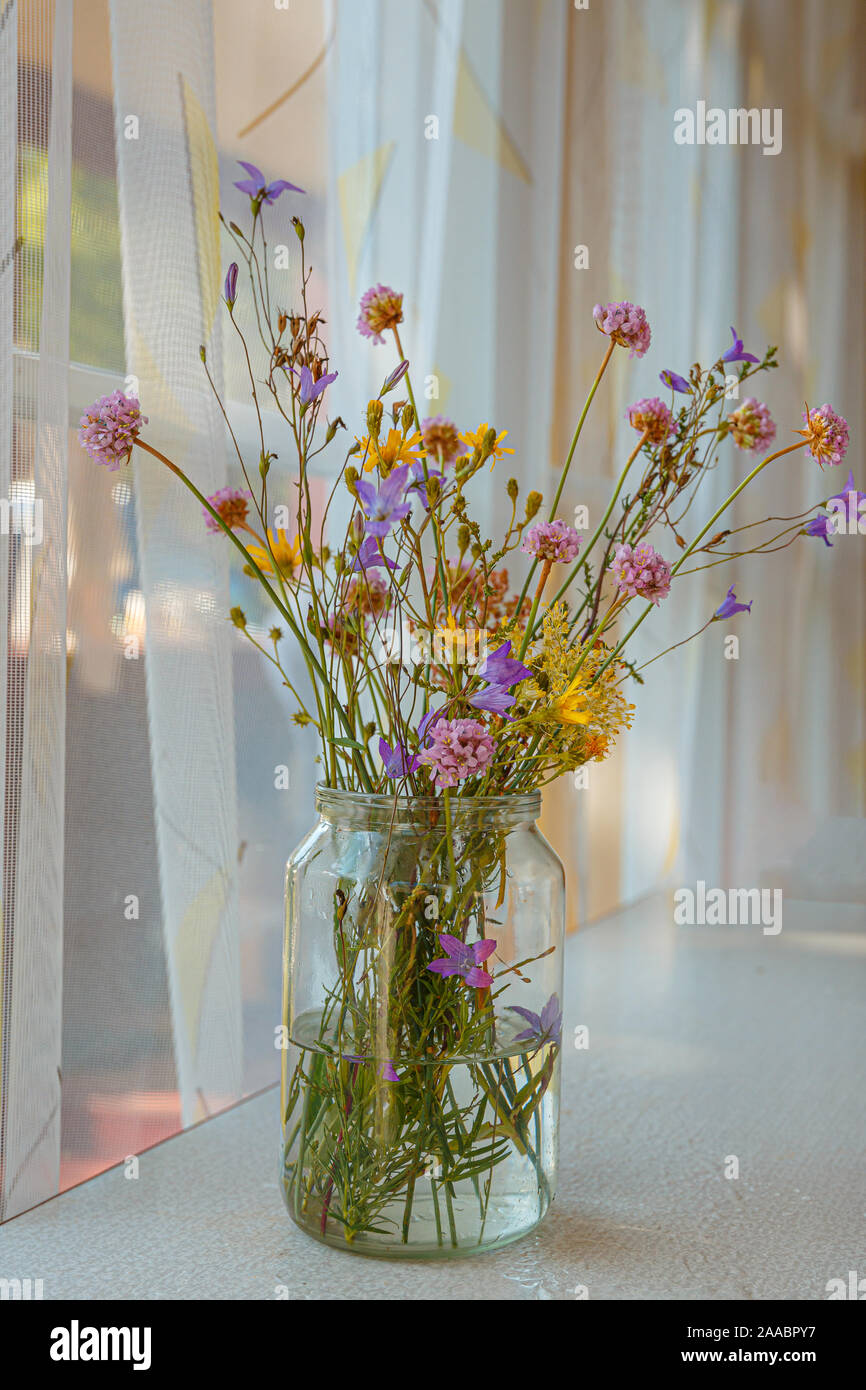 Beautiful bouquet of wild flowers against the background of a window in ...