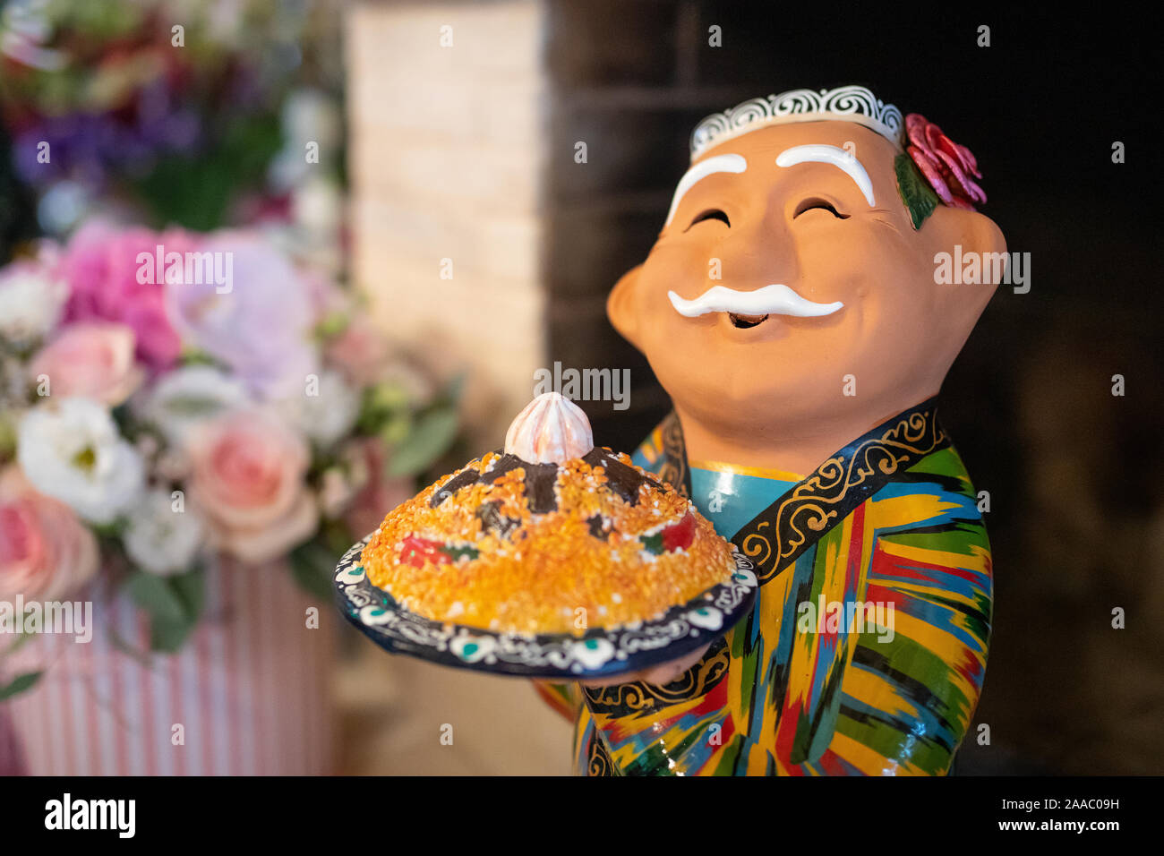 Figure of a toy man in Uzbek national costume with a plate of pilaf ...