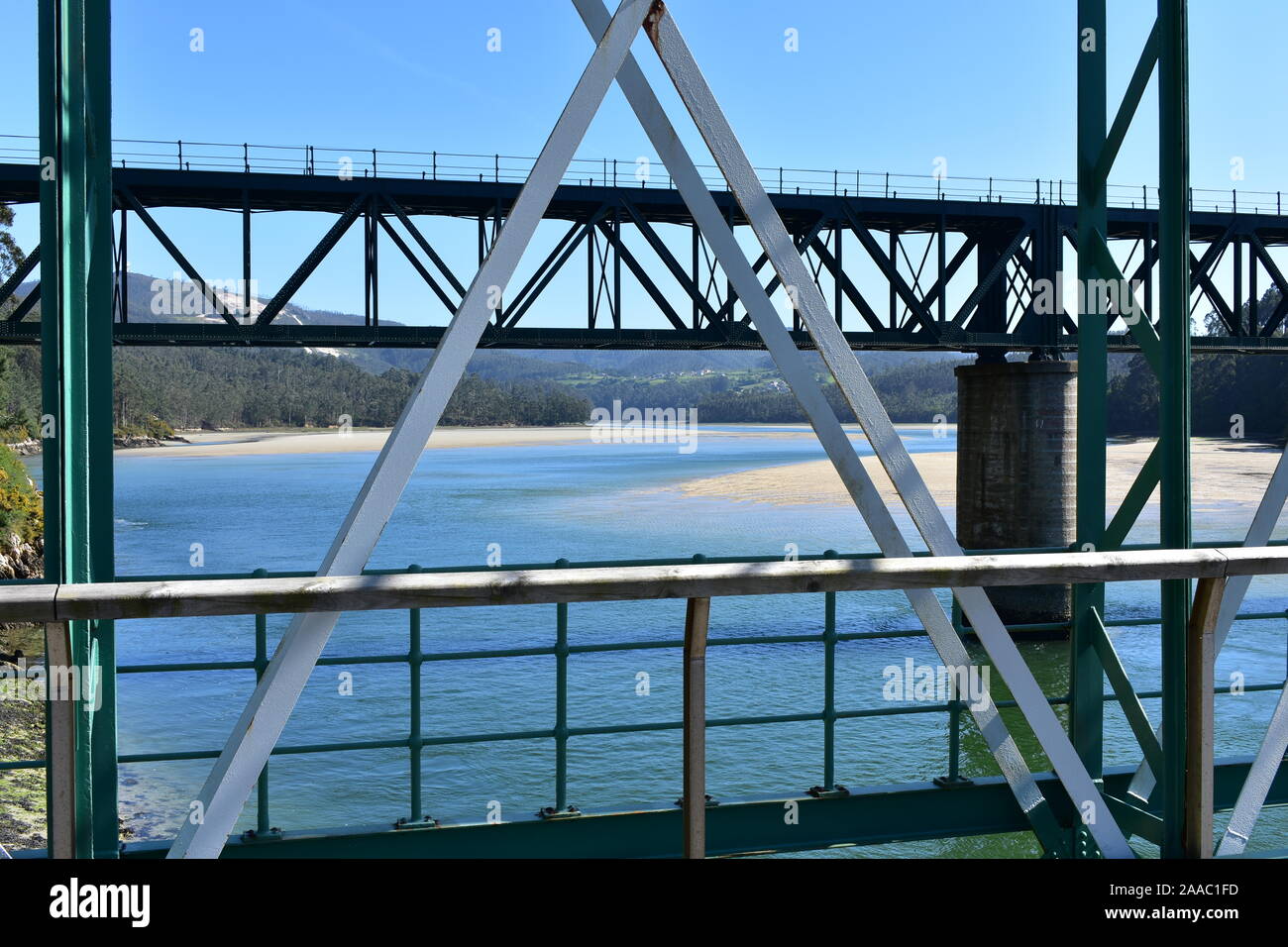 Beach with forest and two train bridges over Sor coastal river. O ...