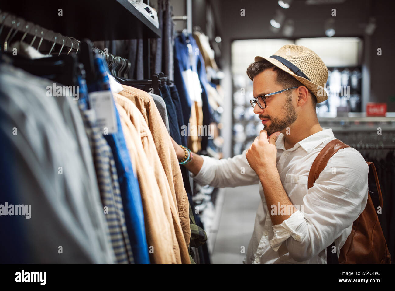 Handsome man shopping for new clothes in store Stock Photo - Alamy