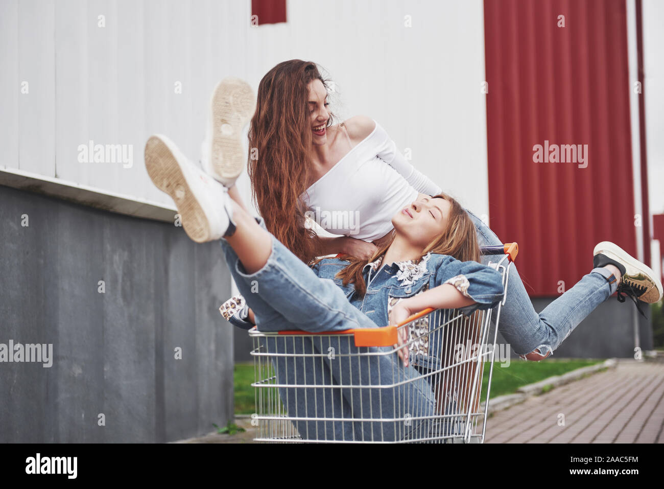 Two young happy women having fun shopping trolley race outdoors Stock ...