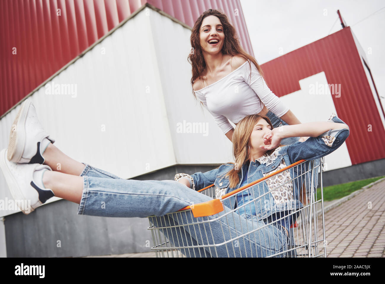 Two young happy women having fun shopping trolley race outdoors Stock ...