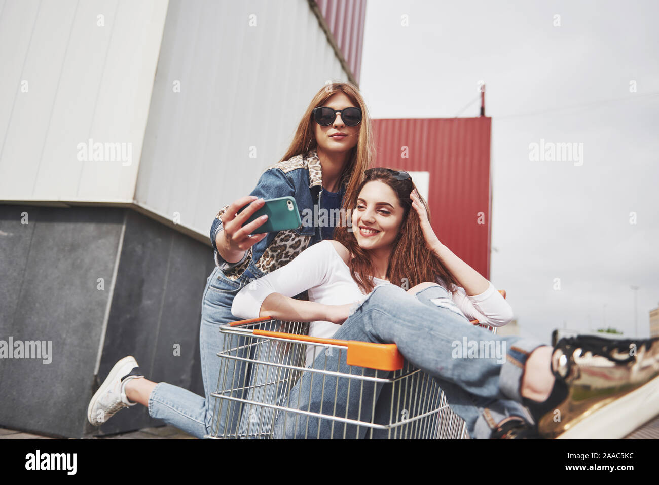 Two young happy women having fun shopping trolley race outdoors Stock ...