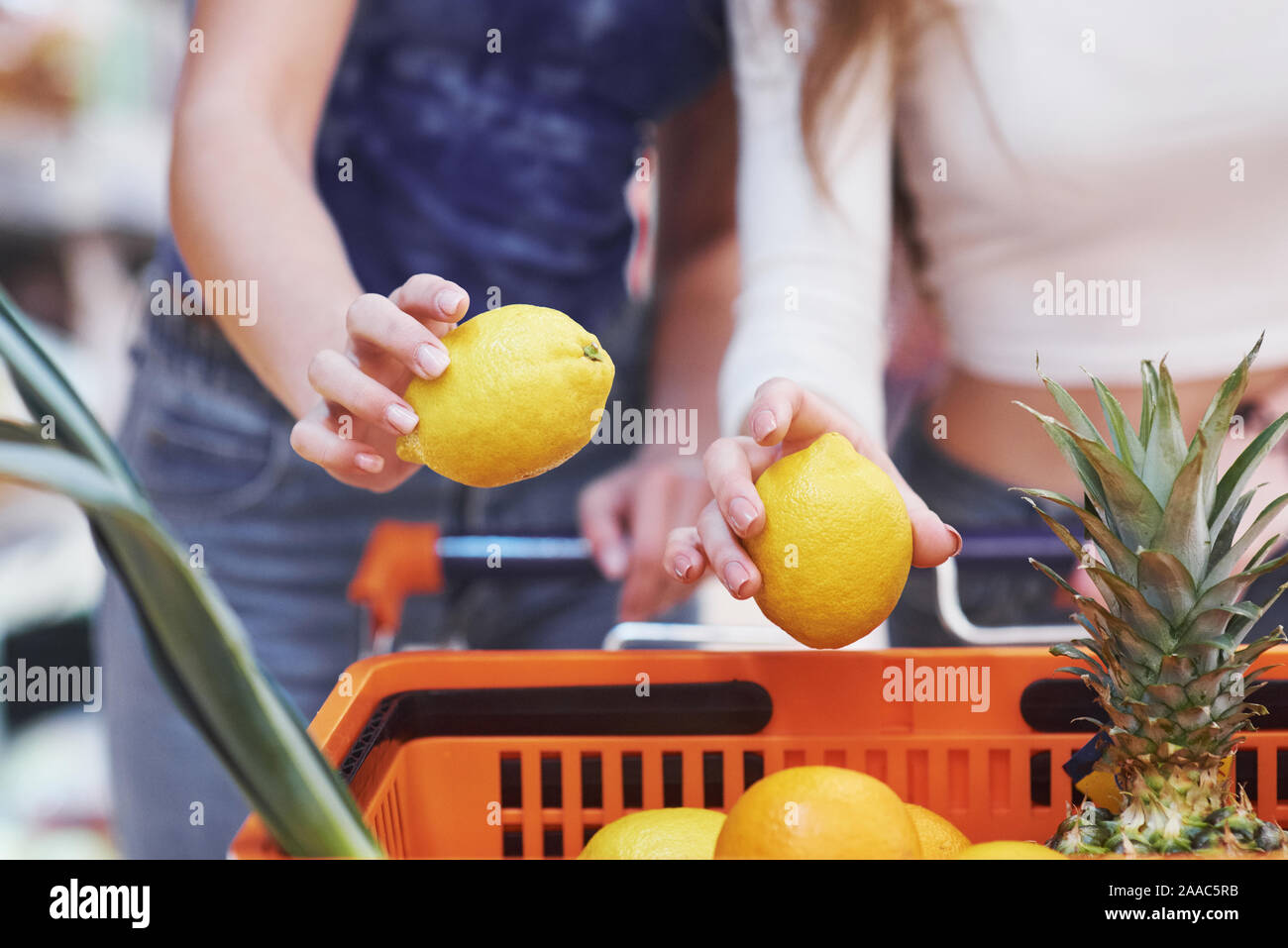 Two women choose seasonal fruits in the supermarket grocery store Stock ...