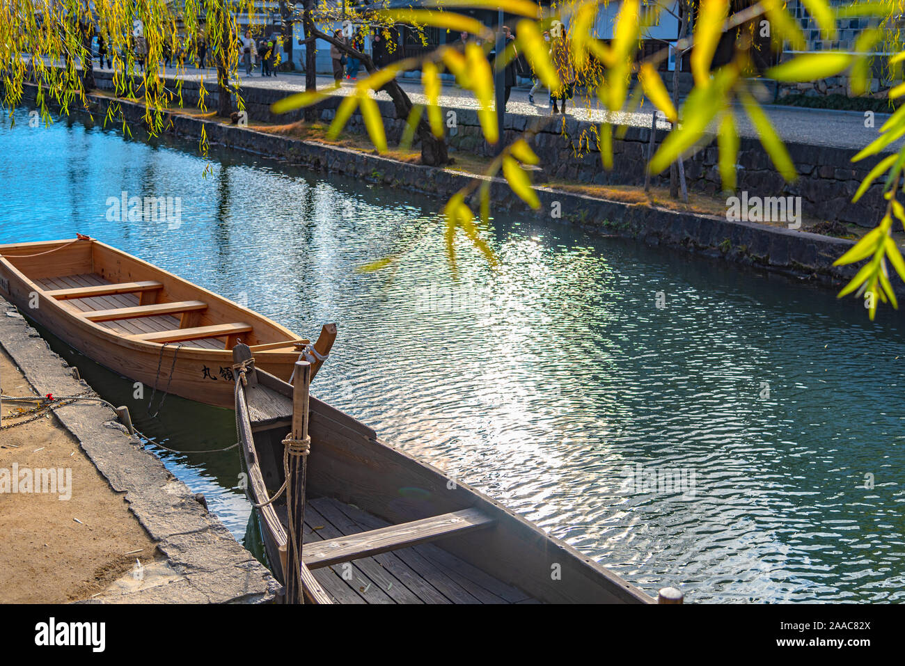 View of traditional wooden boat docked on the river bank with willow ...