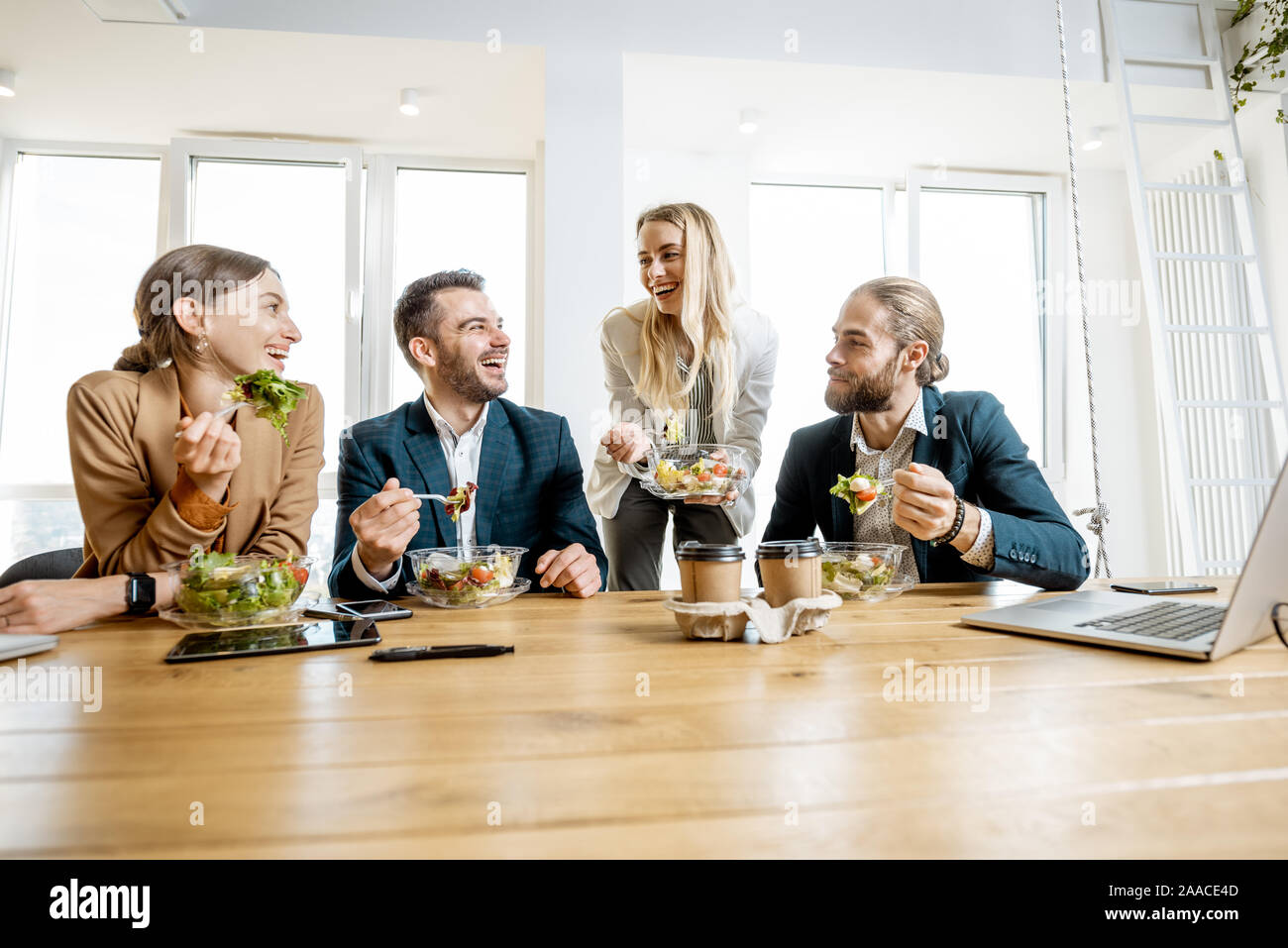Group of a young office workers eating salads and drinking coffee at ...