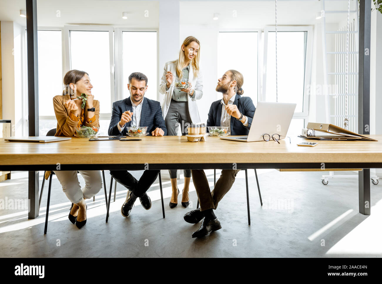 Group of a young office workers eating salads and drinking coffee at ...
