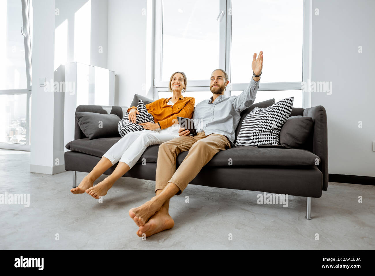 Happy young couple sitting together on the couch in the bright living ...