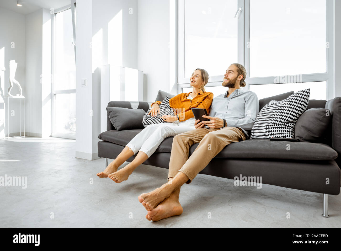 Happy young couple sitting together on the couch in the bright living ...