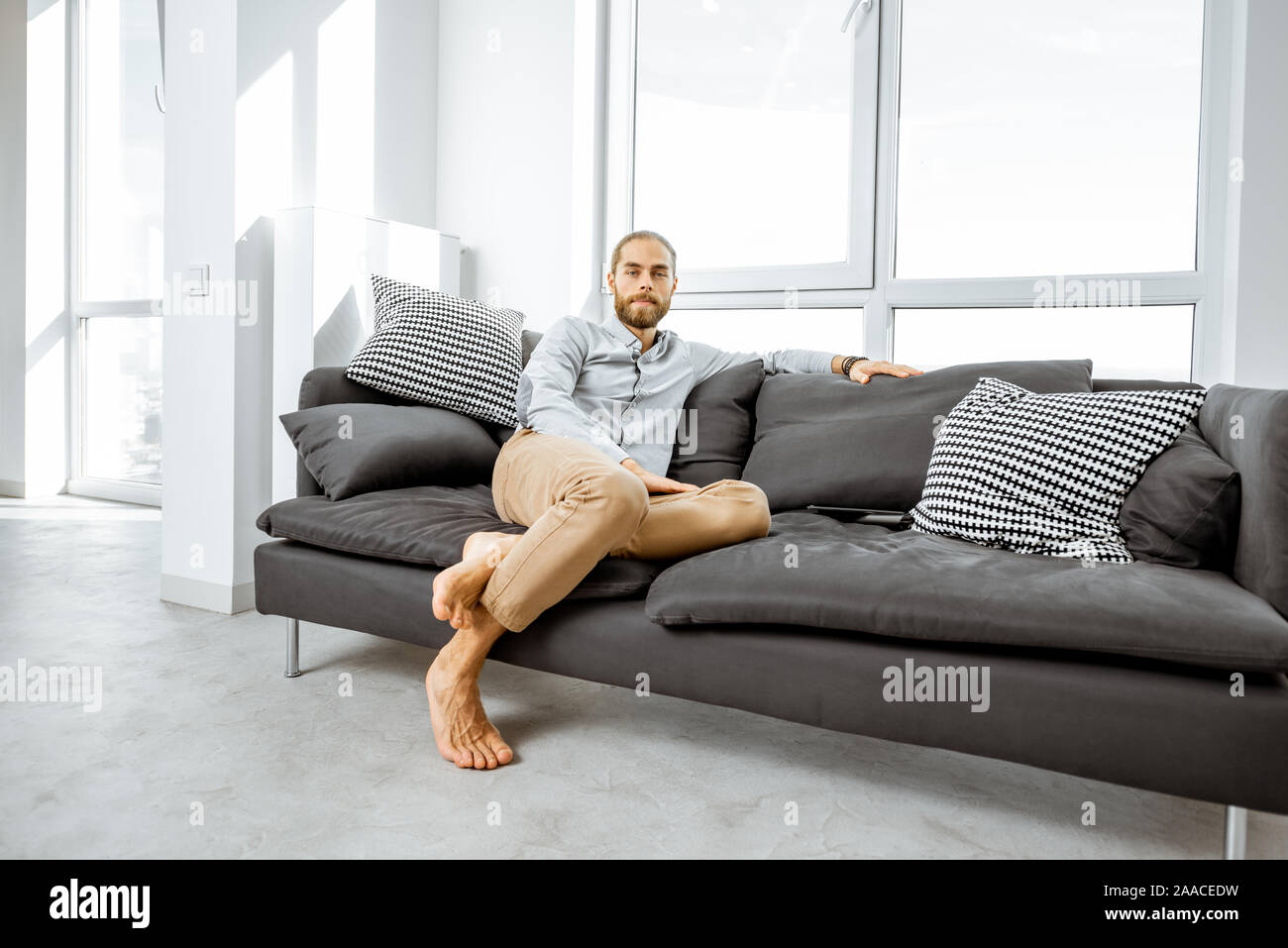 Full length portrait of a handsome caucasian man sitting on the couch ...