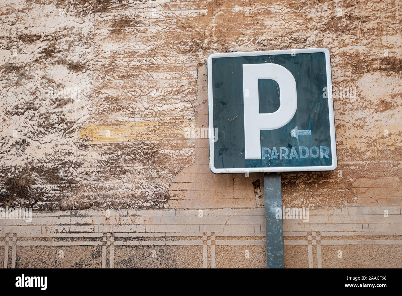 old weathered parking road sign against a stucco old wall with an arrow ...