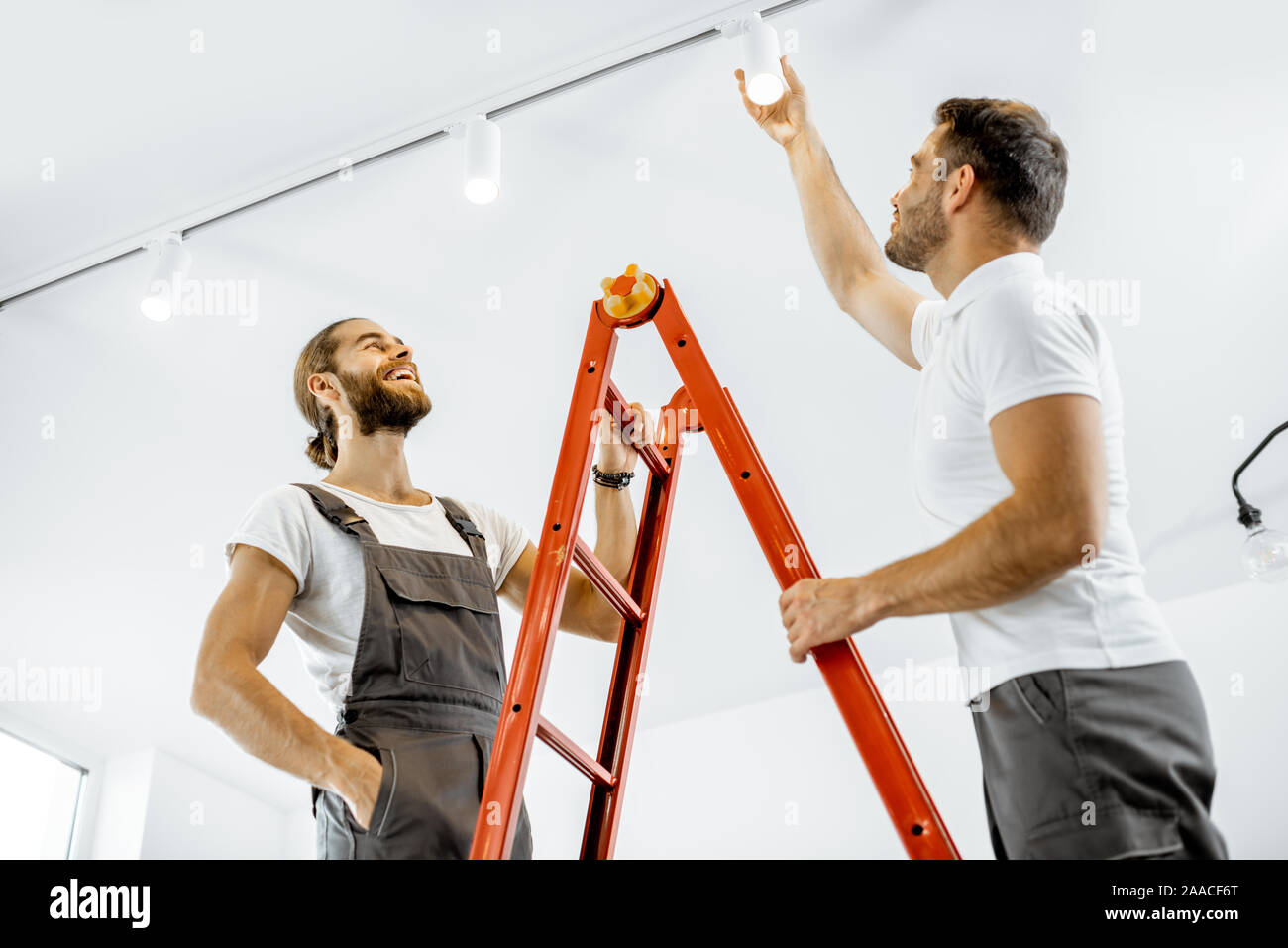 Two repairmen or professional electricians installing light spots ...