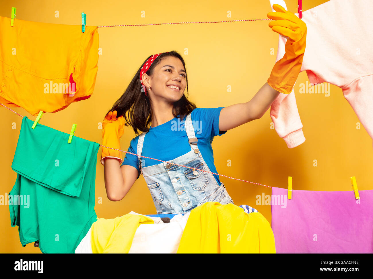 Funny and beautiful housewife doing housework isolated on yellow ...