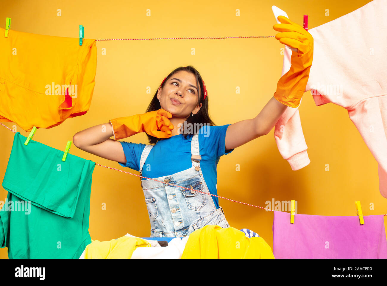 Funny and beautiful housewife doing housework isolated on yellow ...