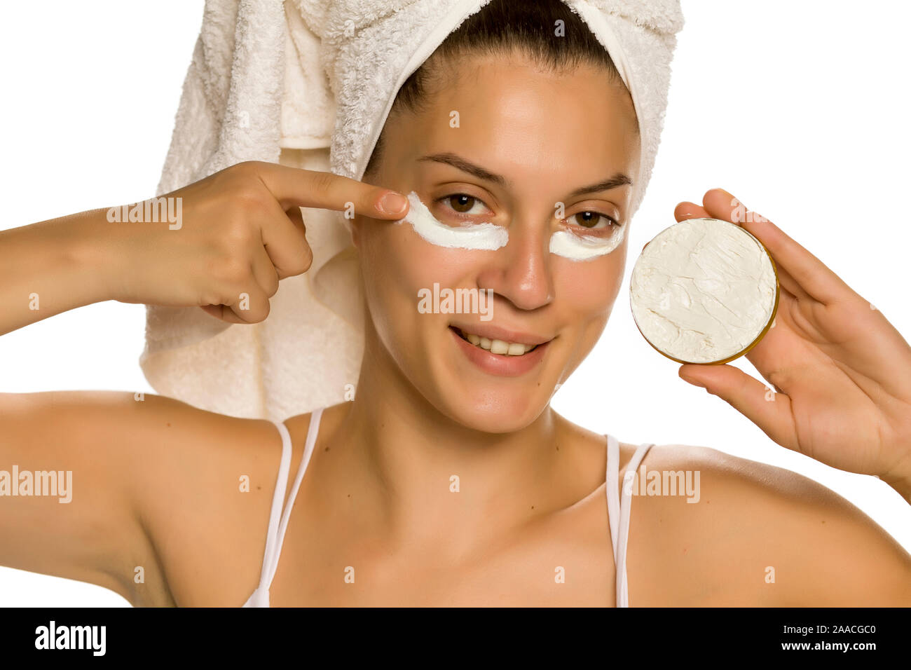 Young Smiling Woman Applying Face Cream Under Her Eyes On White