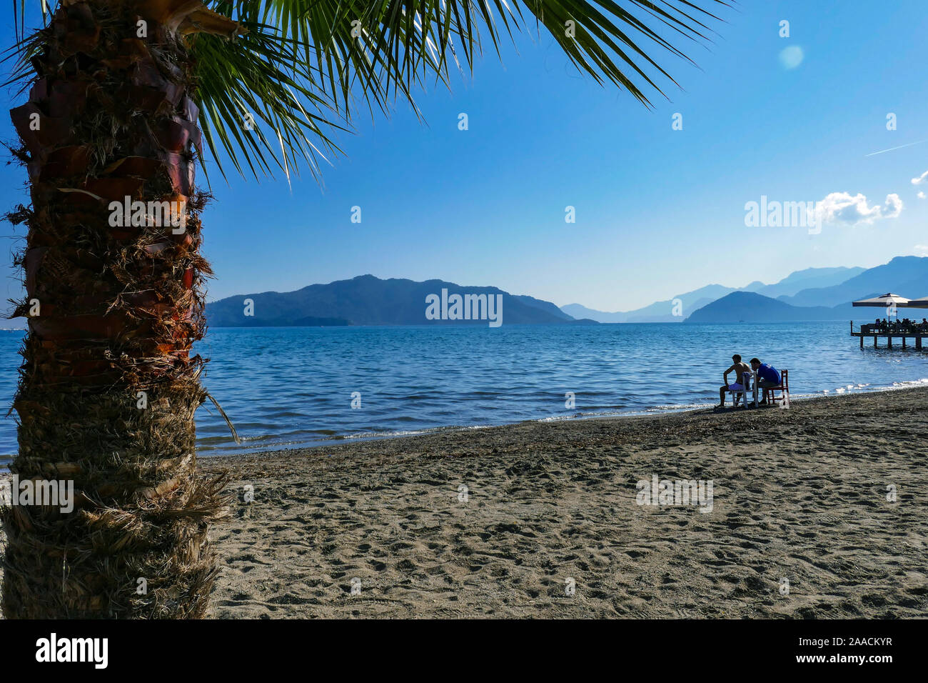 Two men sat on chairs on beach in Marmaris holiday resort, Mugla ...