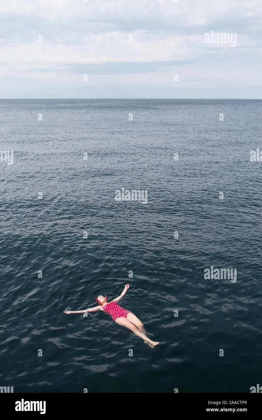 Woman in red swimsuit floating on her back in dark water Stock Photo ...