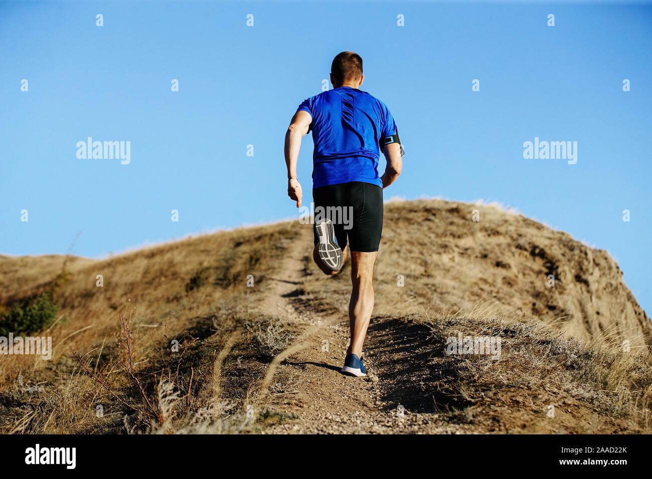 back male runner run uphill on mountain trail near the cliff Stock ...