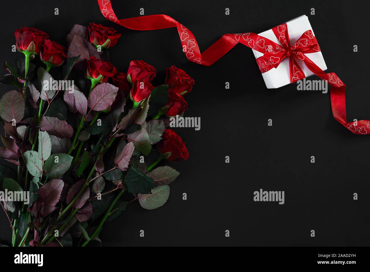 Red roses, ring and gift box on black background Stock Photo - Alamy