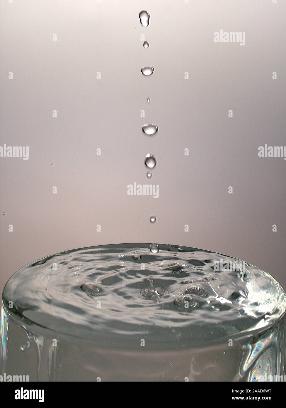 drops falling in glass full of water Stock Photo - Alamy