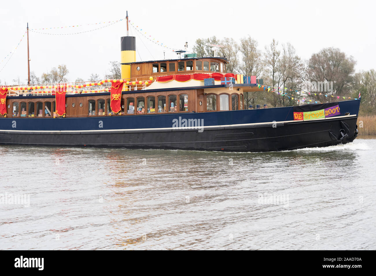 Traditional steamboat sailing on the water with festive clothing and ...
