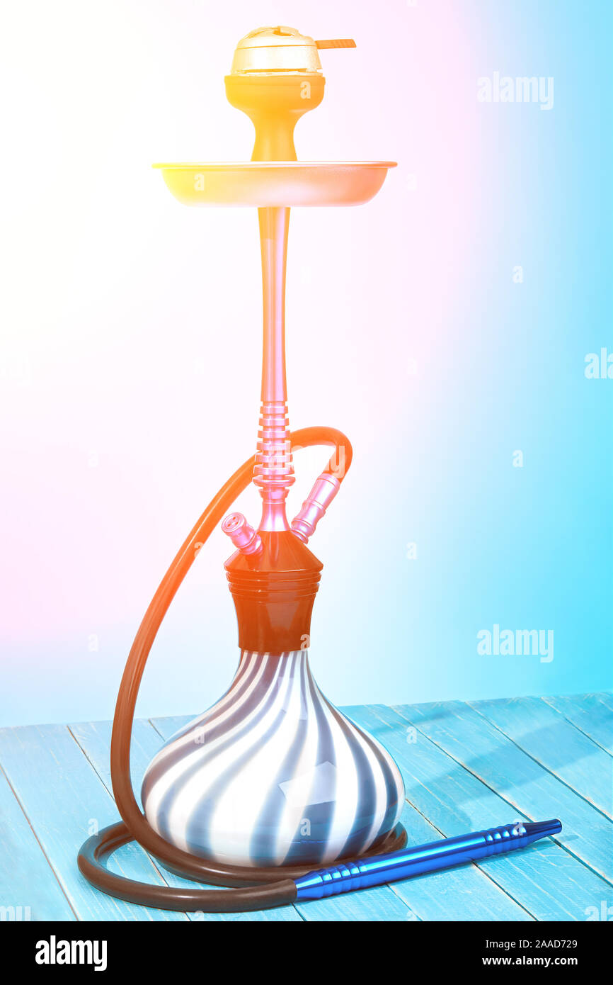 Blue hookah with black rubber tube and blue and white flask on light ...