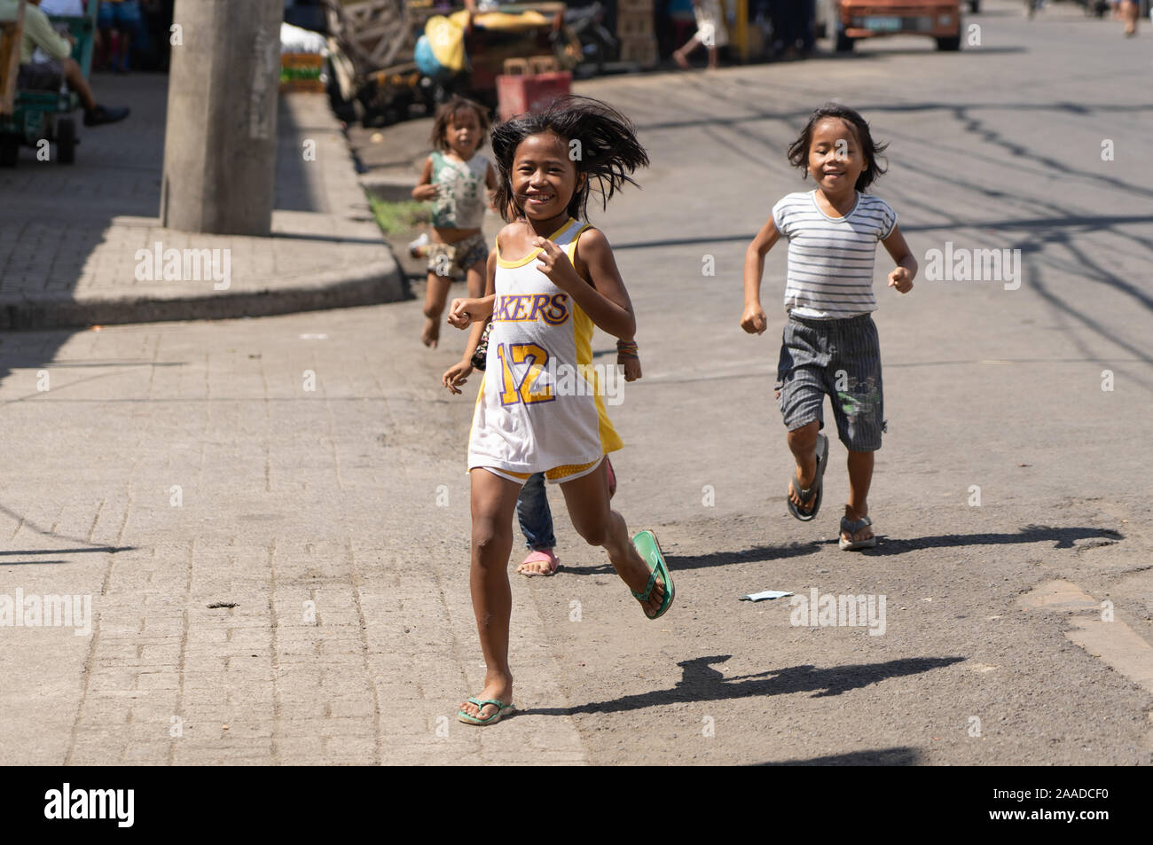 A group of young Filipino children running through a downtown street in ...
