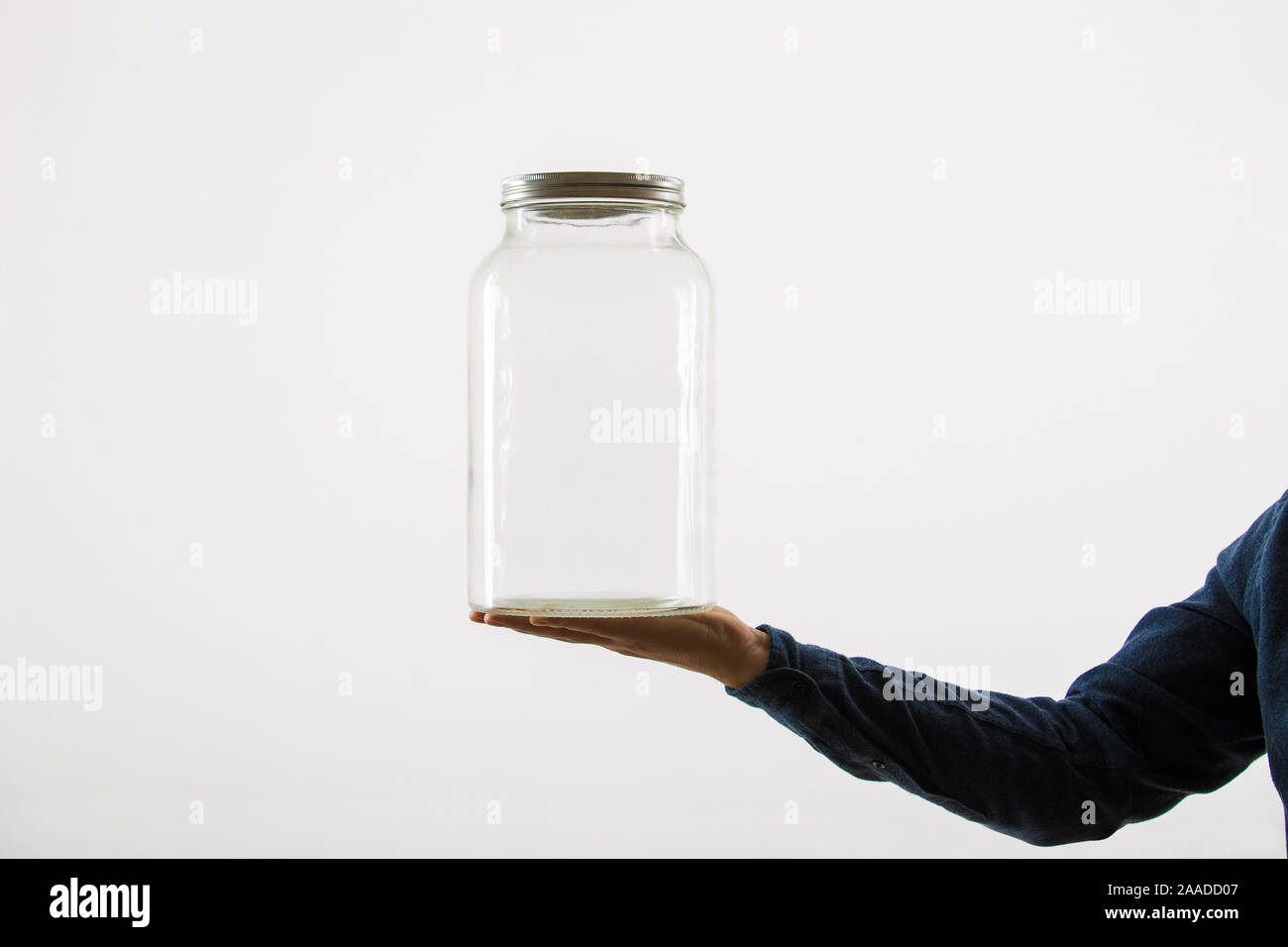 Close up of person hand holding an empty glass jar isolated over white ...