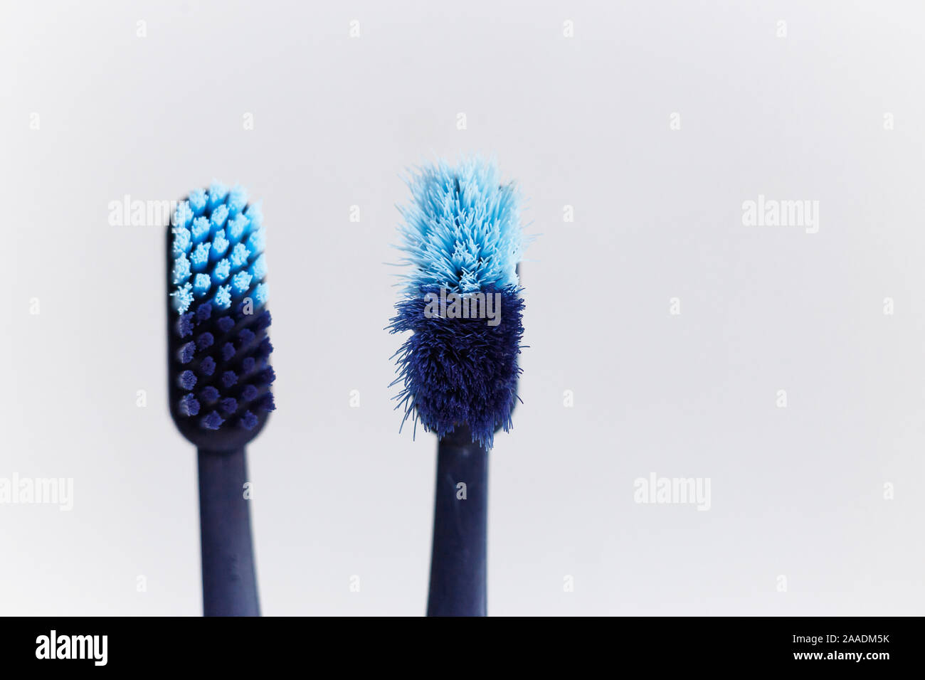 New and used blue color toothbrush in cup on white Stock Photo - Alamy