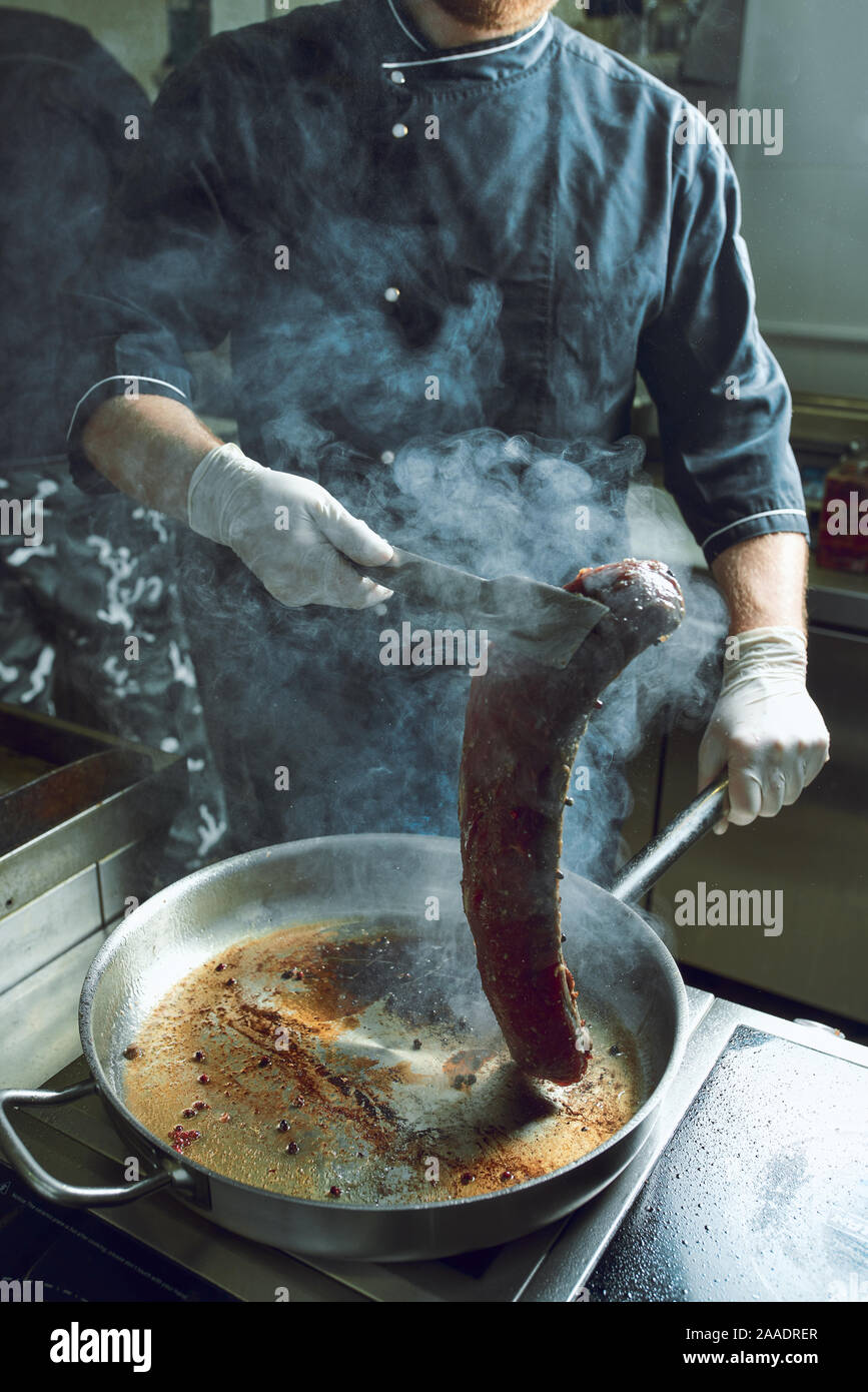 The chef works in the kitchen of the restaurant. Fresh meat roasted in ...