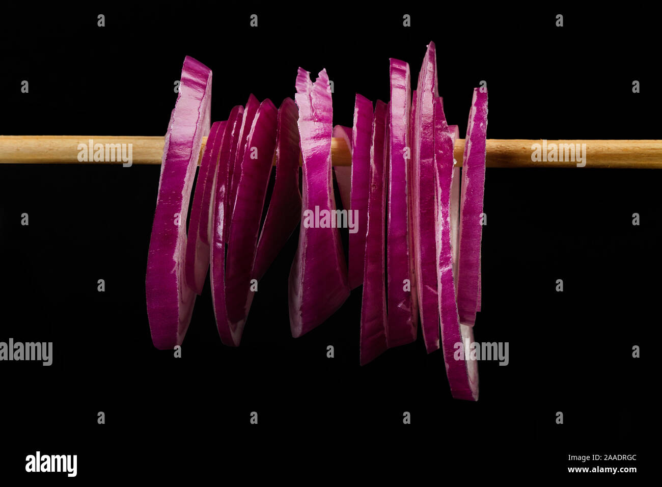 Slices of a purple onion hanging from a wooden stick Stock Photo - Alamy