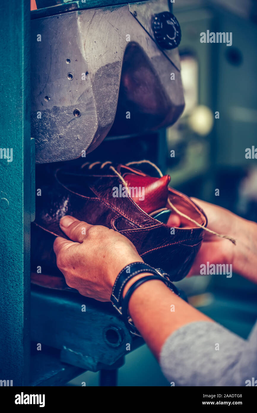 Experienced shoemaker using a special machine for putting shoes on the ...