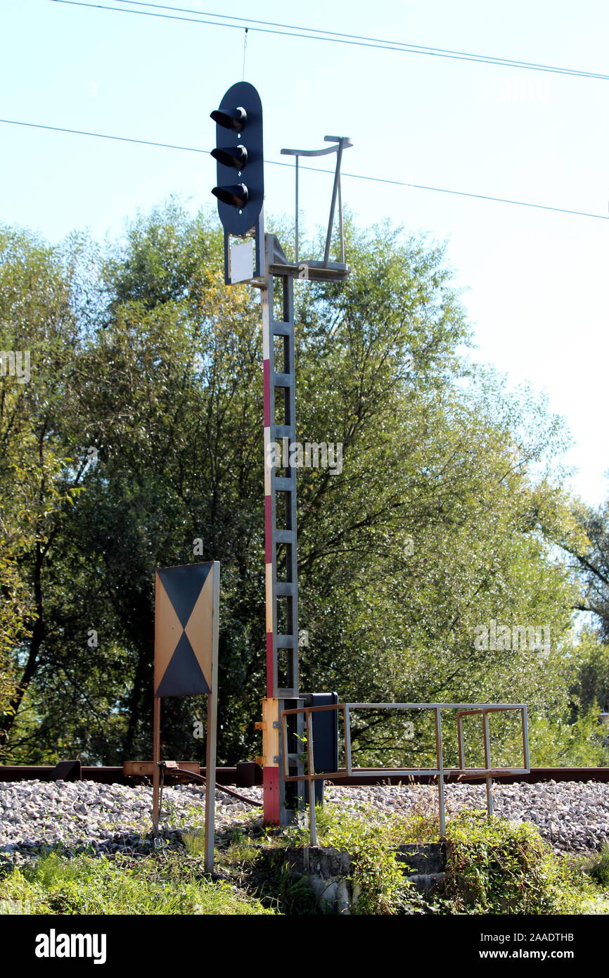 Tall railway tracks traffic light mounted on strong metal pole next to ...