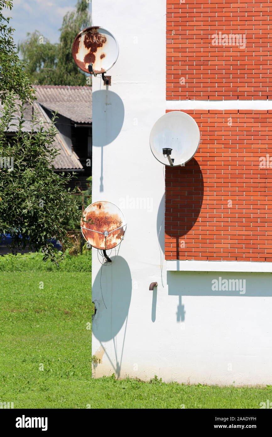 Two old almost completely rusted and one newer satellite dishes mounted ...