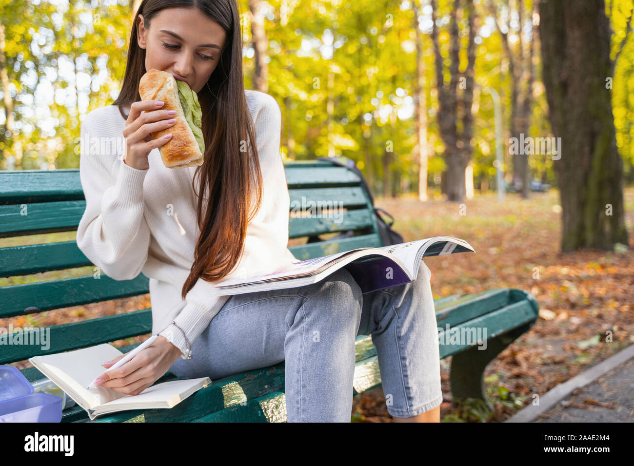 Serious long-haired female eating while reading book Stock Photo - Alamy