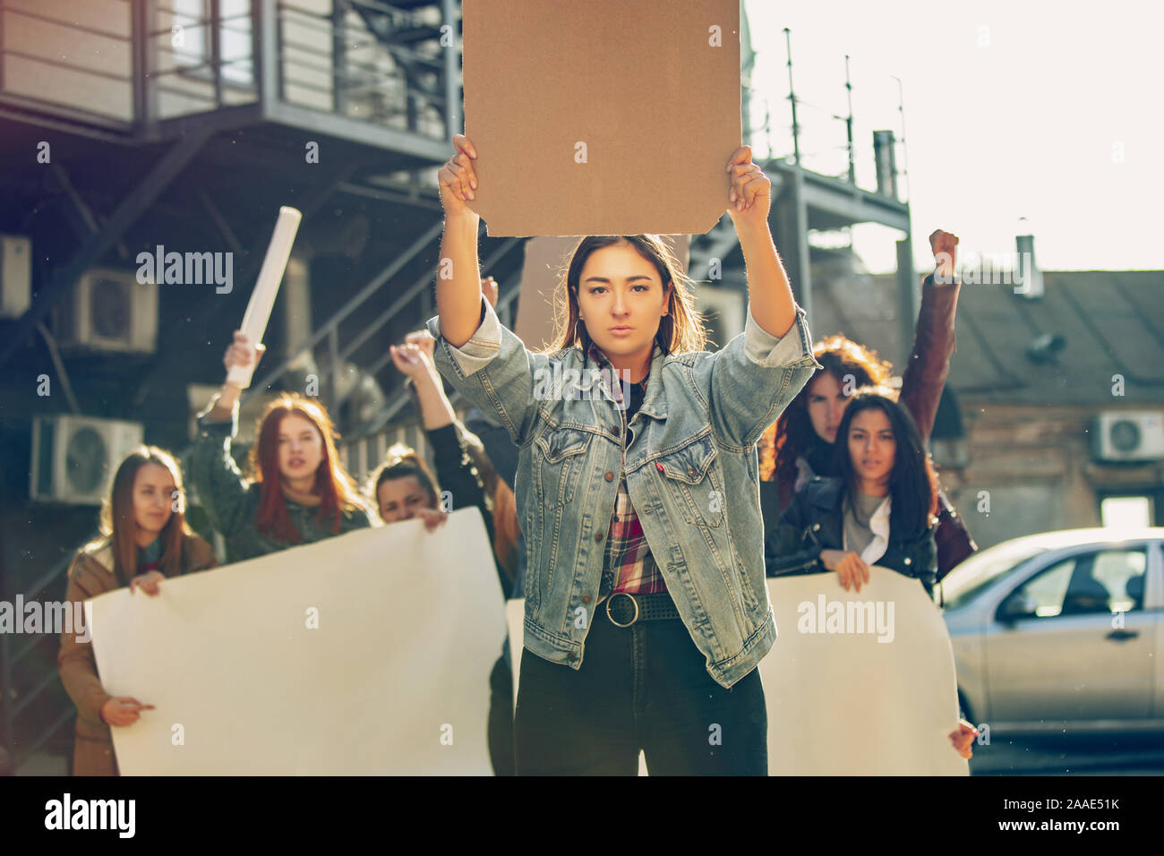 Young woman with blank poster in front of people protesting about women ...