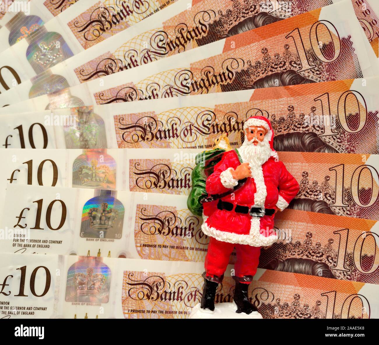A santa claus figurine standing in front of some new ten pound notes ...