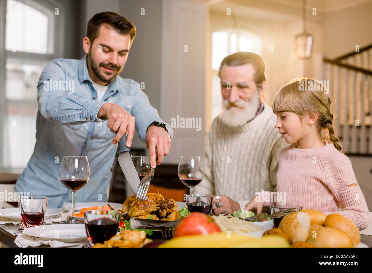 Smiling father cutting slices of turkey for family dinner. Family with ...