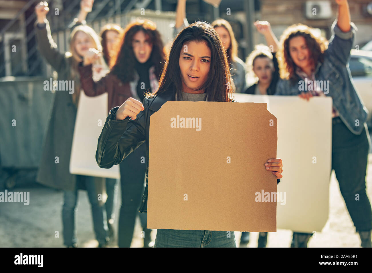 Young woman with blank poster in front of people protesting about women ...