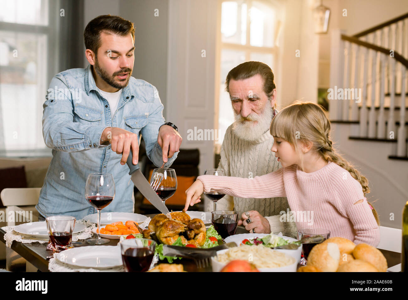 Image of handsome man father showing how to cut roasted turkey to his ...