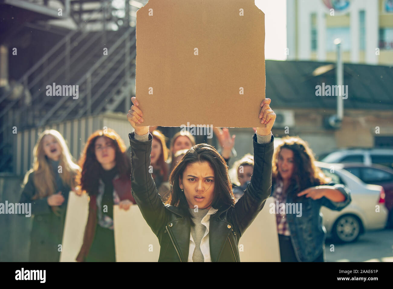Young woman with blank poster in front of people protesting about women ...