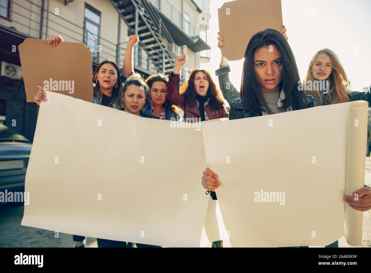 Young woman with blank poster in front of people protesting about women ...