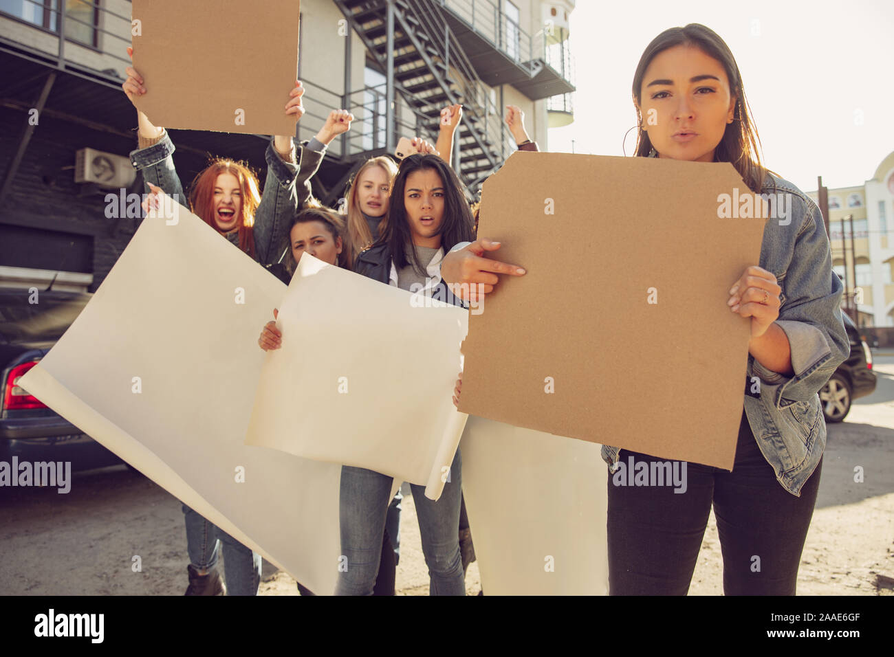 Young woman with blank poster in front of people protesting about women ...