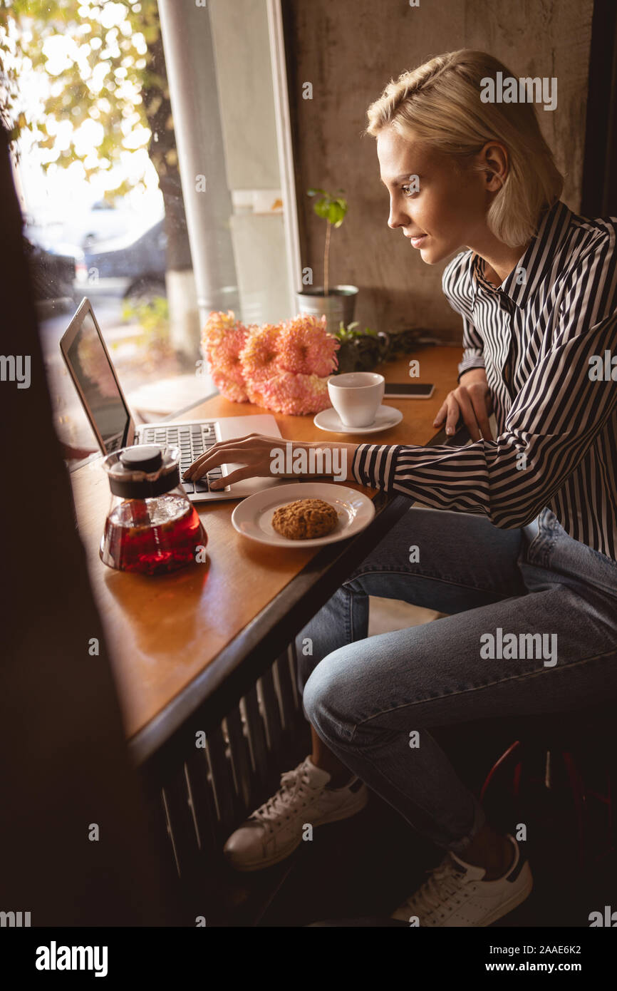 Pretty woman typing a message on her laptop Stock Photo - Alamy
