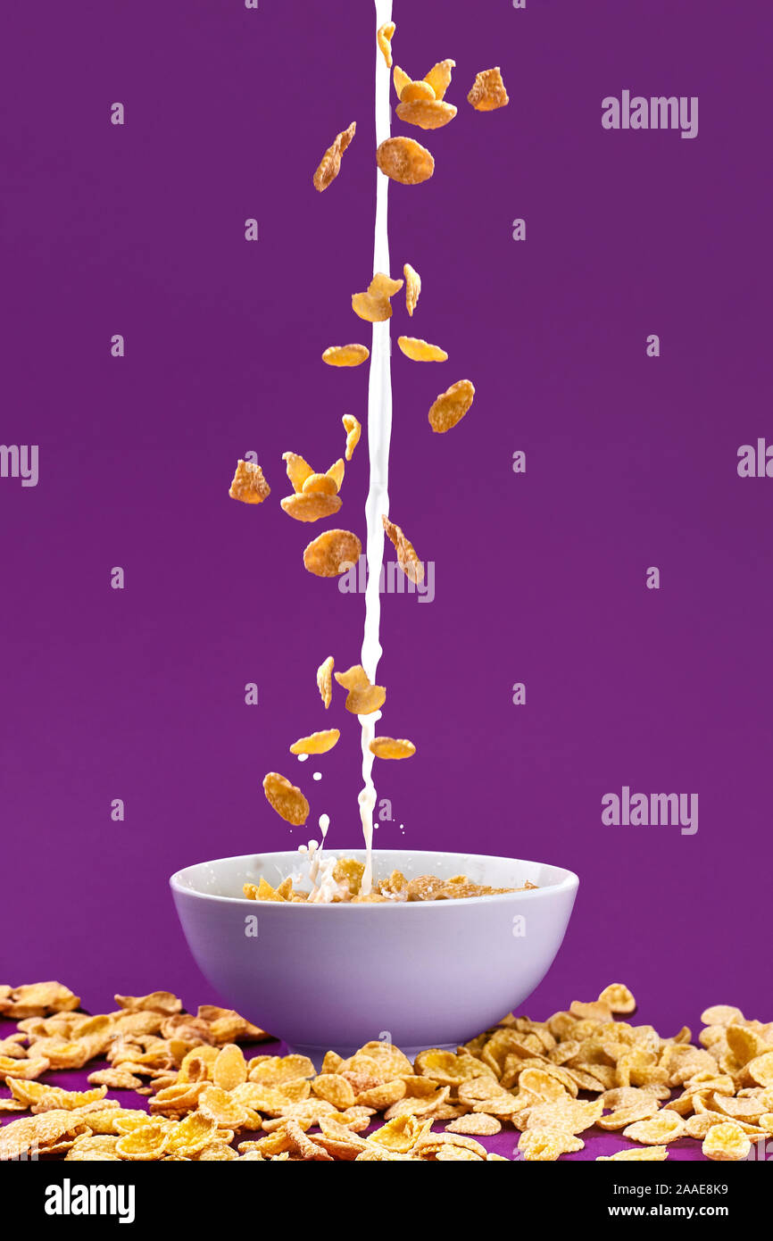 Falling granola with milk splash in bowl. Healthy breakfast ingredients ...