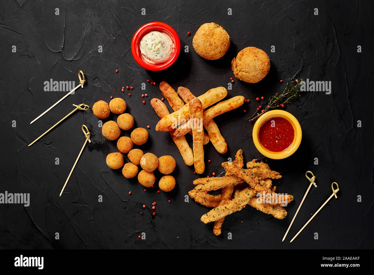 Allsorts of fried snacks with two different sauces on black background ...