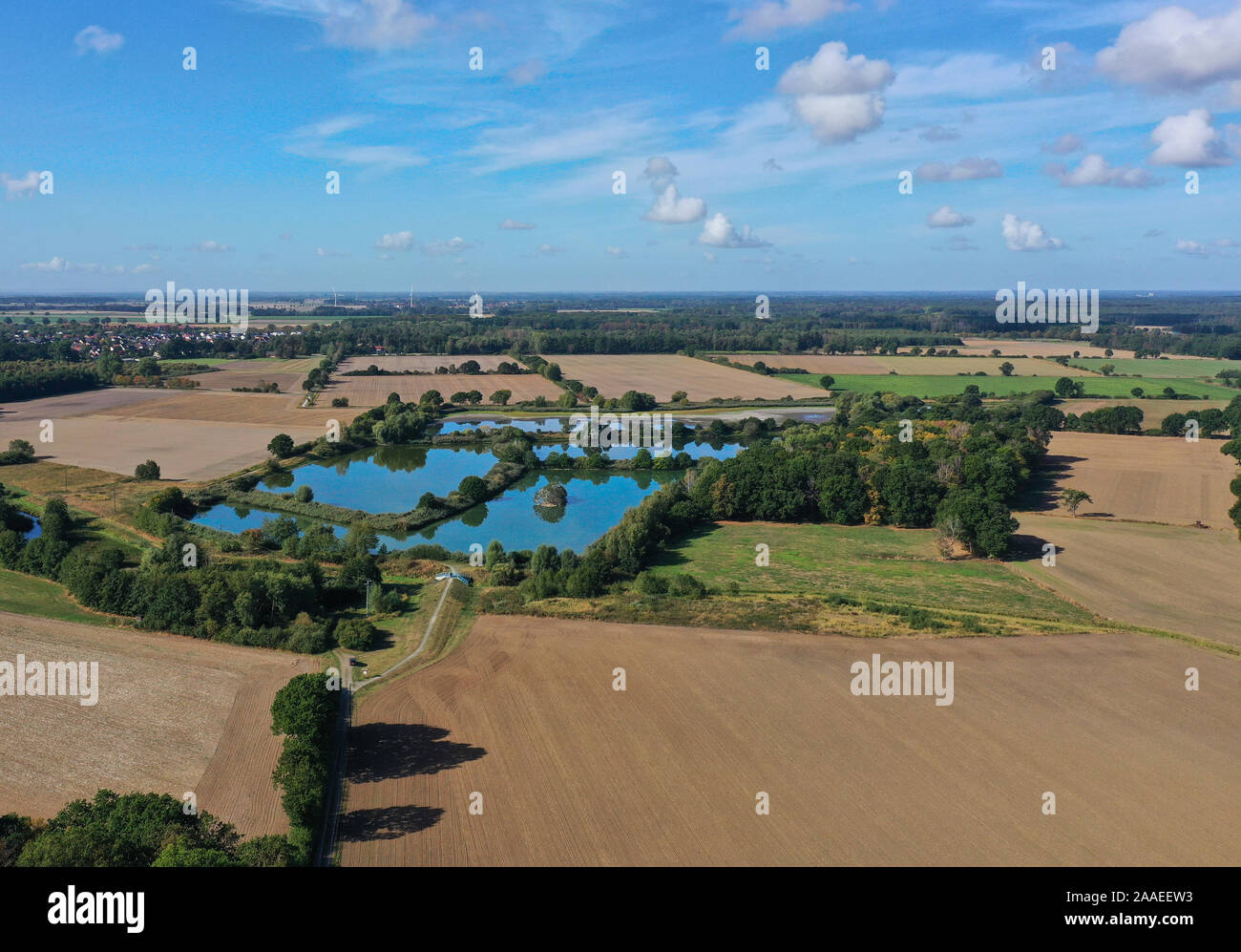 Aerial view of fish ponds with blue water between fields and ...