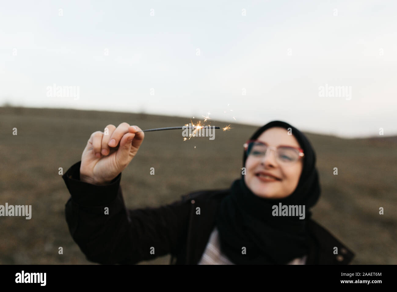 portrait of a beautiful woman with hijab and glasses holding sprinkle ...