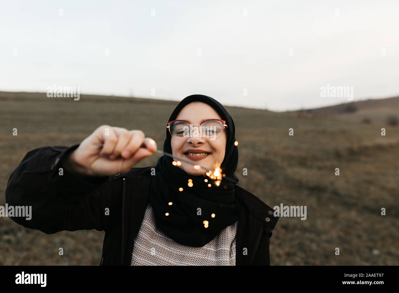 portrait of a beautiful woman with hijab and glasses holding sprinkle ...
