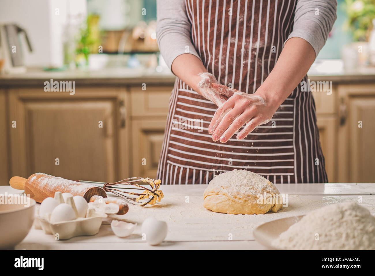 Woman slap his hands above dough closeup. Baker finishing his bakery ...
